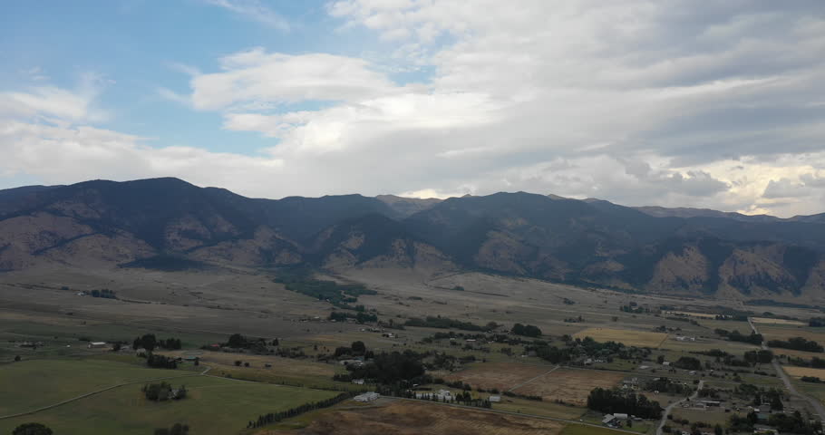 Clouds and farm landscape with town and mountains in Montana image ...
