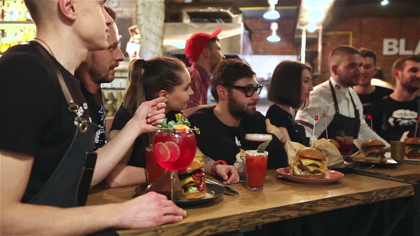 The Staff Of The Restaurant Eating Burgers And Drinking Cocktails At A ...