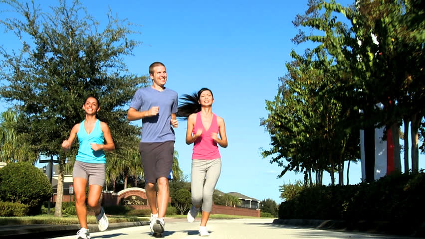 Young Friends Keeping Fit Together Jogging Outdoors On Suburban Roads ...