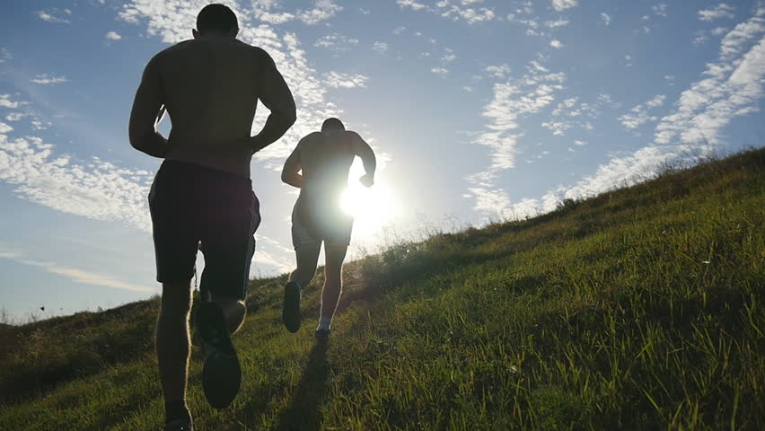 Young Men Running Over Green Hill Over Blue Sky Background. Male ...