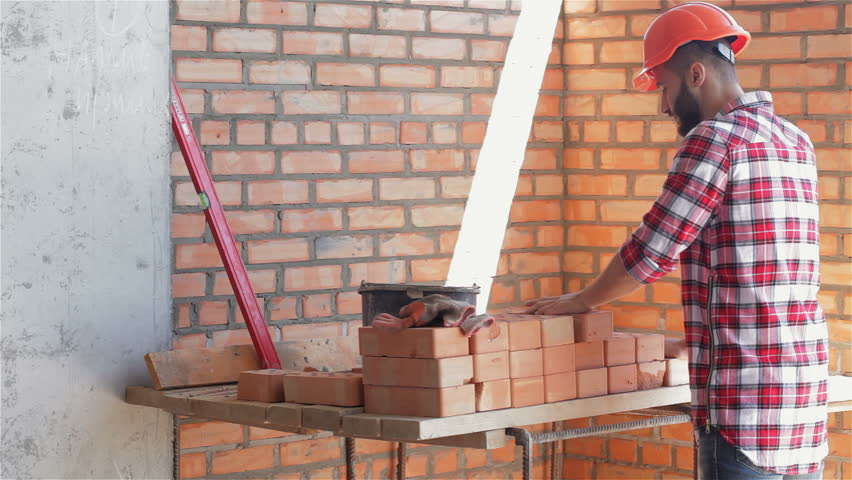 Stockvideoclip van Young builder shifting bricks at the building ...