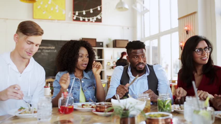 Camera Moves Around Table As Group Of Friends Sit In Cafe Eating And ...