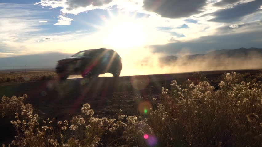SLOW MOTION CLOSEUP Black SUV Car Driving On Empty Gravel Road Raising ...