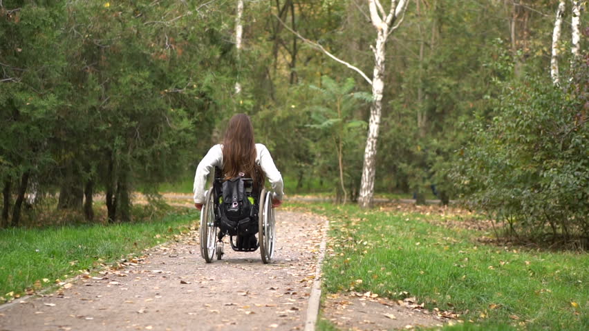 Stock Video Clip of Attractive girl on a wheelchair walking in ...