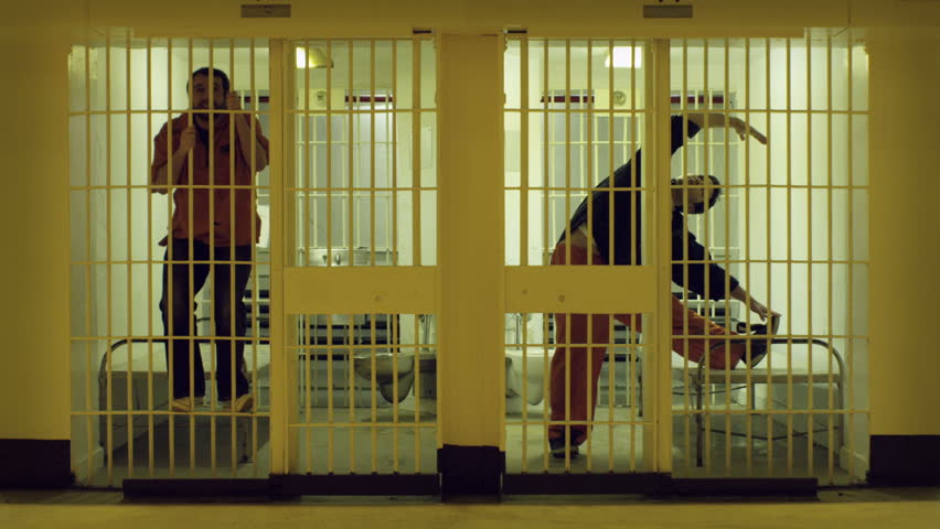 Inmate Gets Up From Bed To Stand At The Bars Of His Prison Cell ...