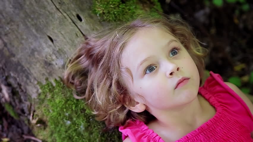 Bird's-Eye View Of Little Girl Laying Down On A Log And Looks Up Into ...